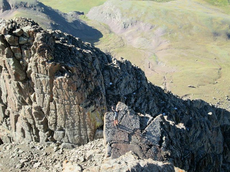 A hiker approaches the summit block. The technical formation behind him ...