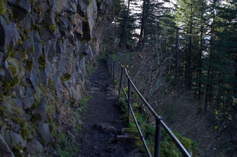 The trail follows the rock face of the cliff as it makes its way toward ...