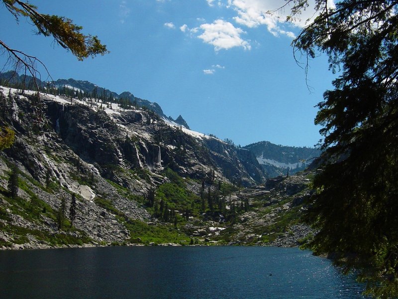 An alpine lake with waterfalls on the granite cliffs high in the ...